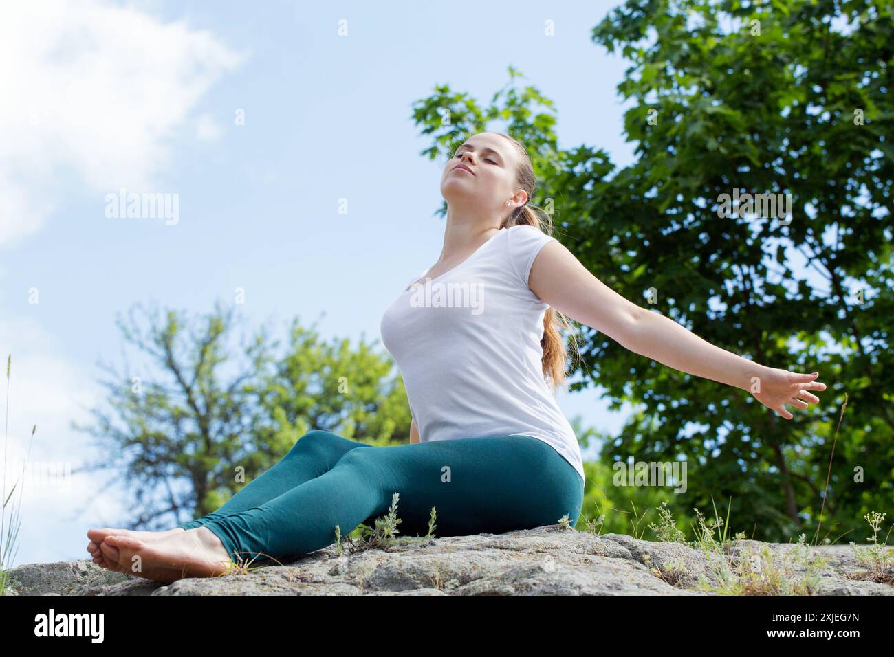 Healthy calm young woman meditating in nature with eyes closed, doing ...