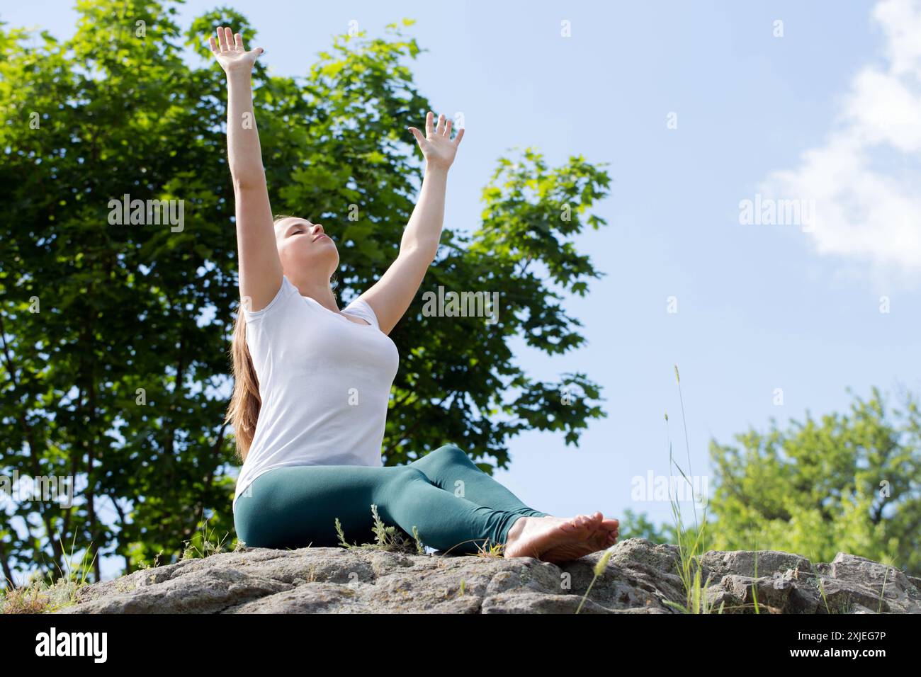 Healthy calm young woman meditating in nature with eyes closed, doing ...