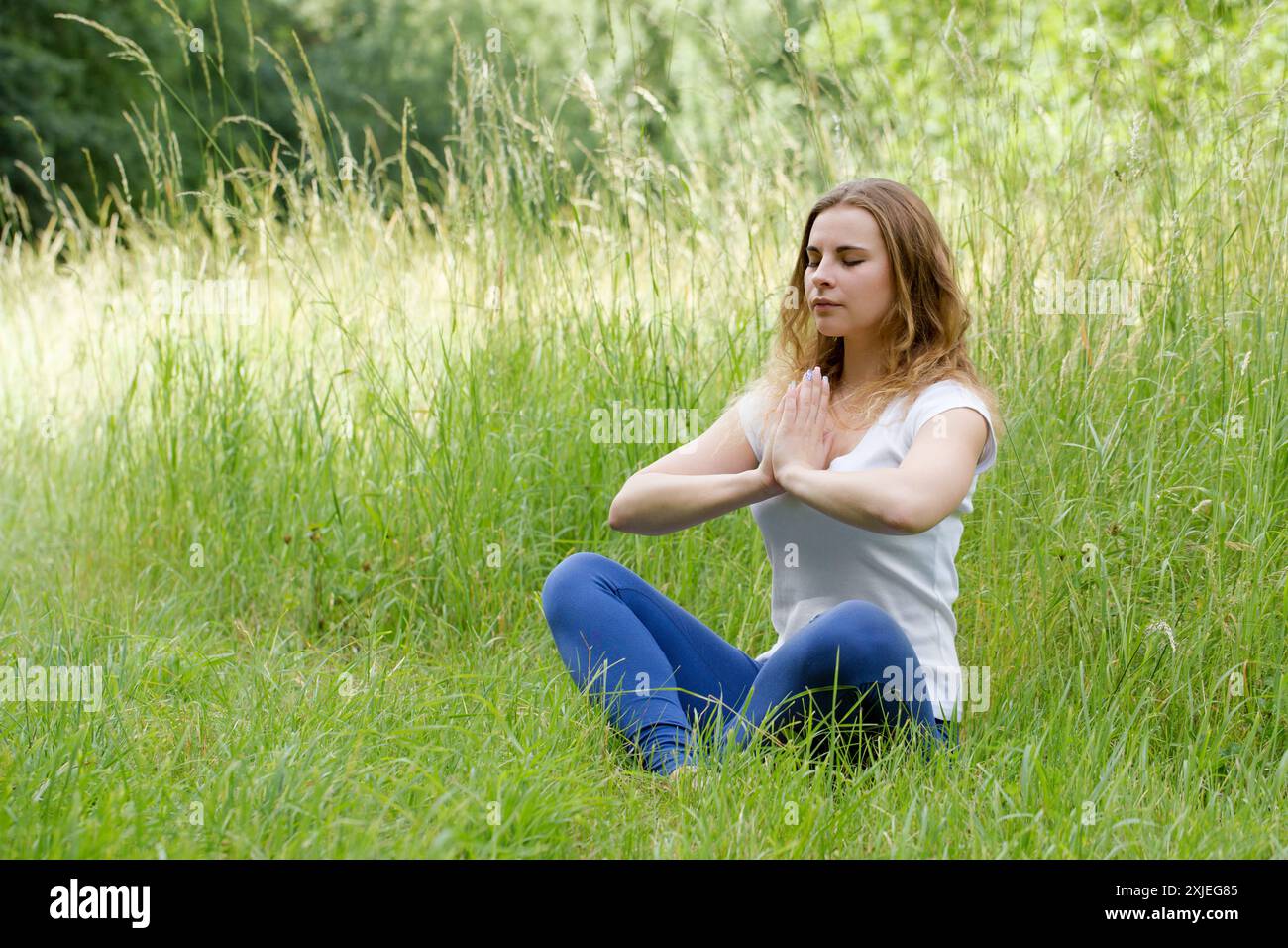 Healthy calm young woman meditating in nature with eyes closed, doing ...