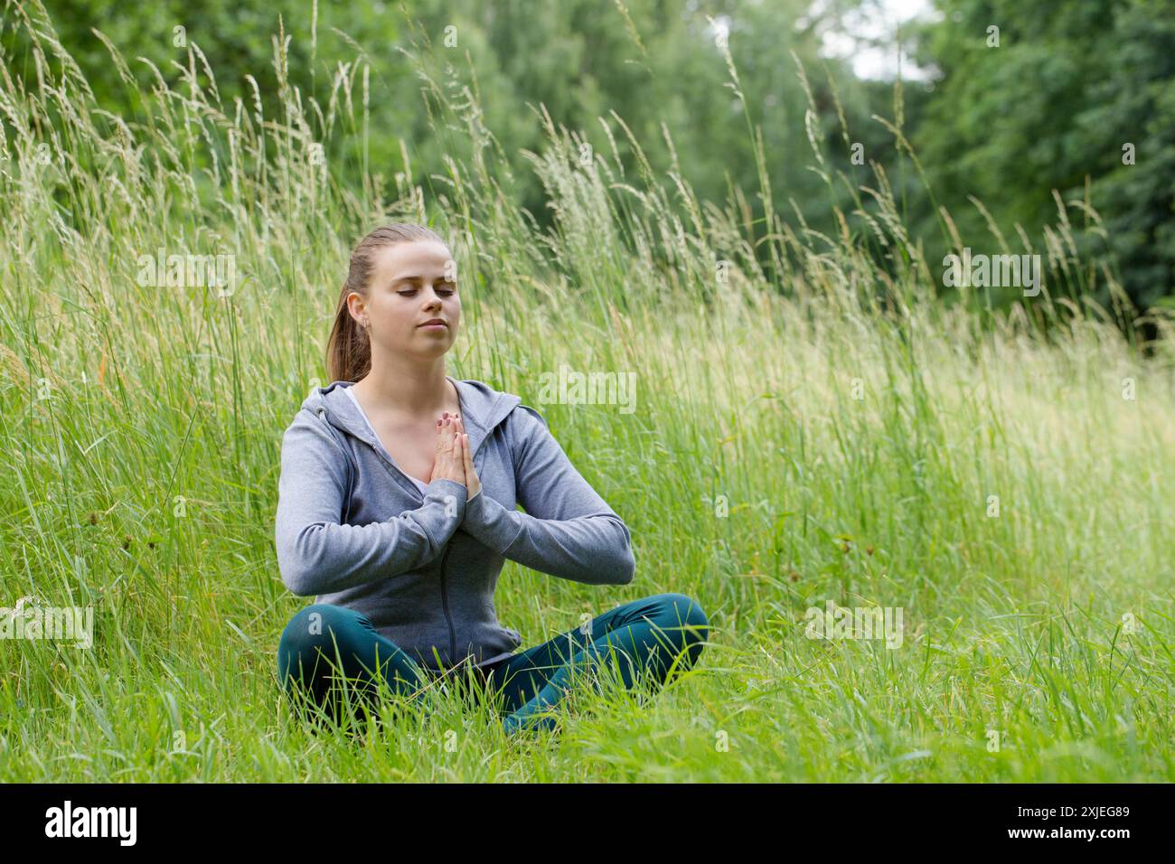 Healthy calm young woman meditating in nature with eyes closed, doing ...