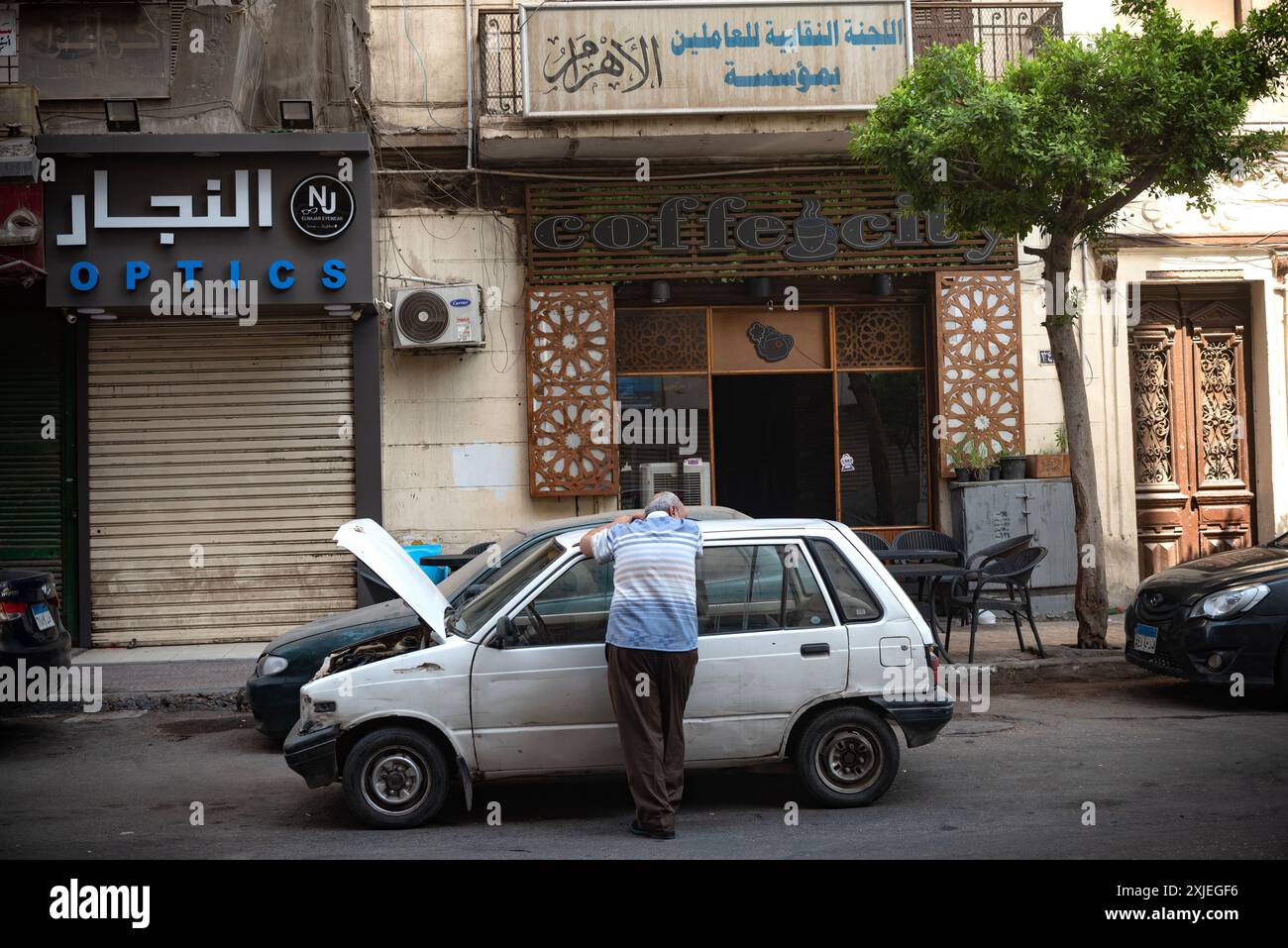 Cairo, Egypt. June 24th 2024 An Egyptian man waits by his broken down car in the summer heat of ...