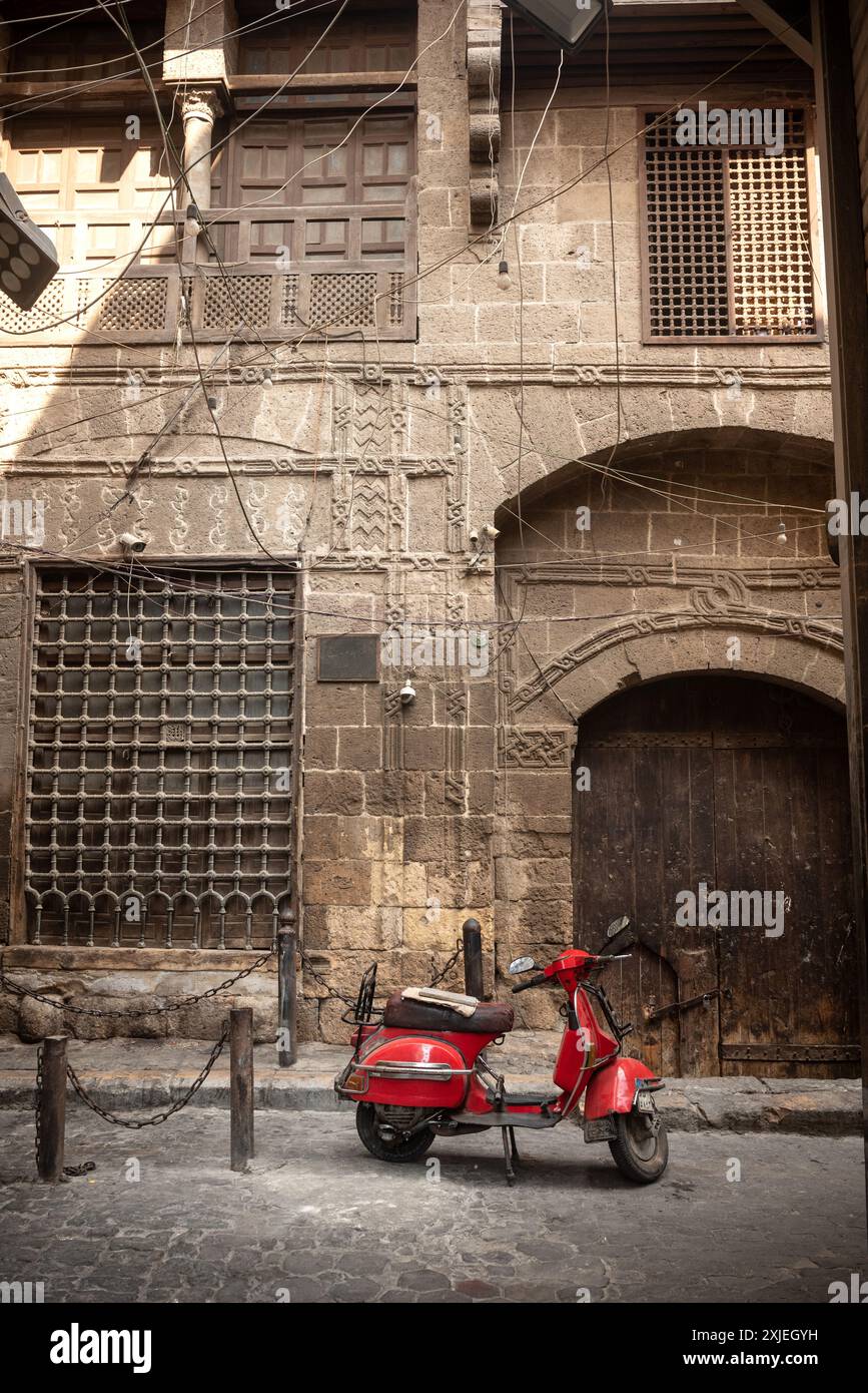 Cairo, Egypt. July 7th 2024 A cool looking red scooter parked in front of typical Egyptian ...