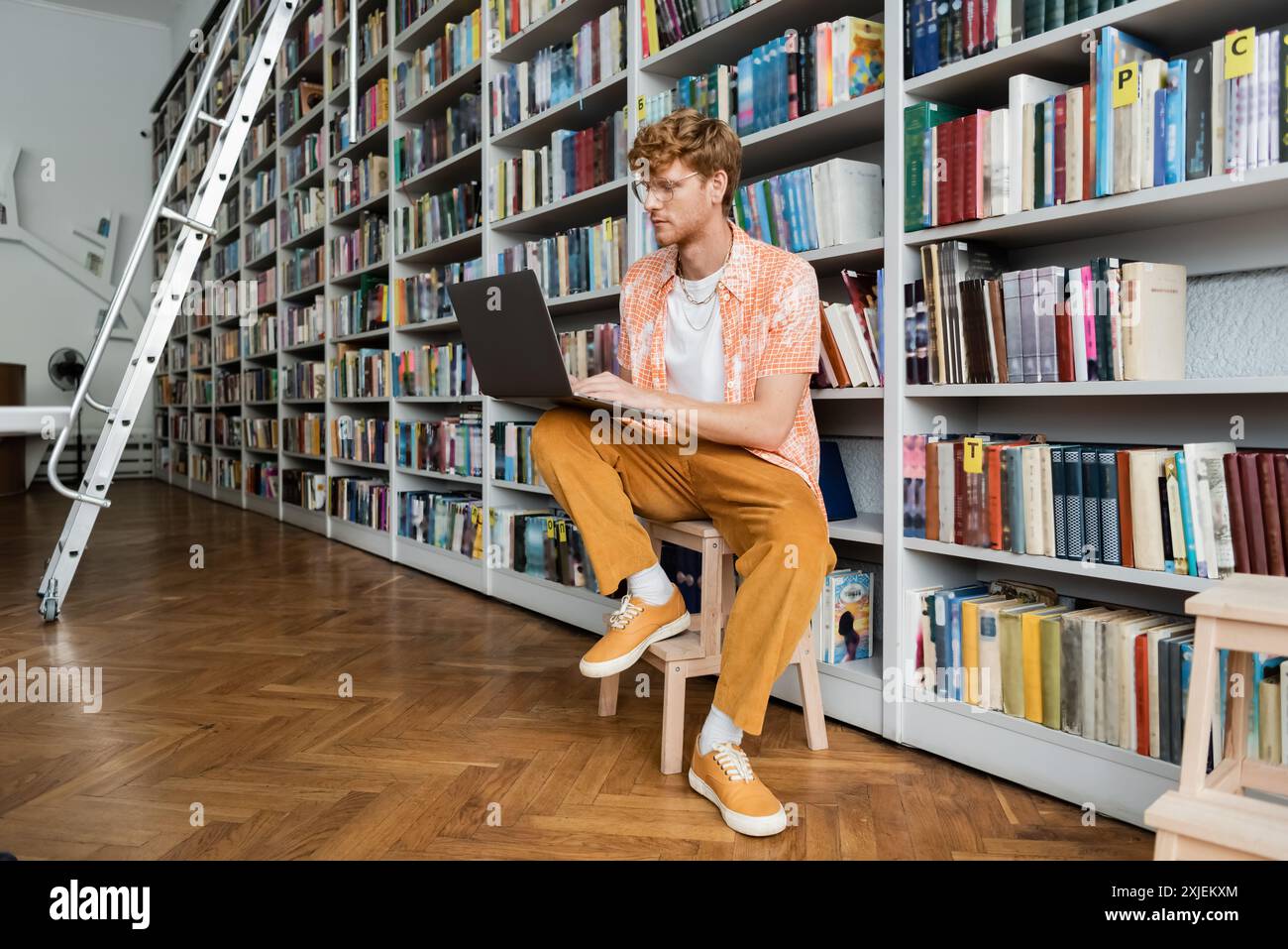 A young man immerses himself in study, typing on a laptop in a library ...