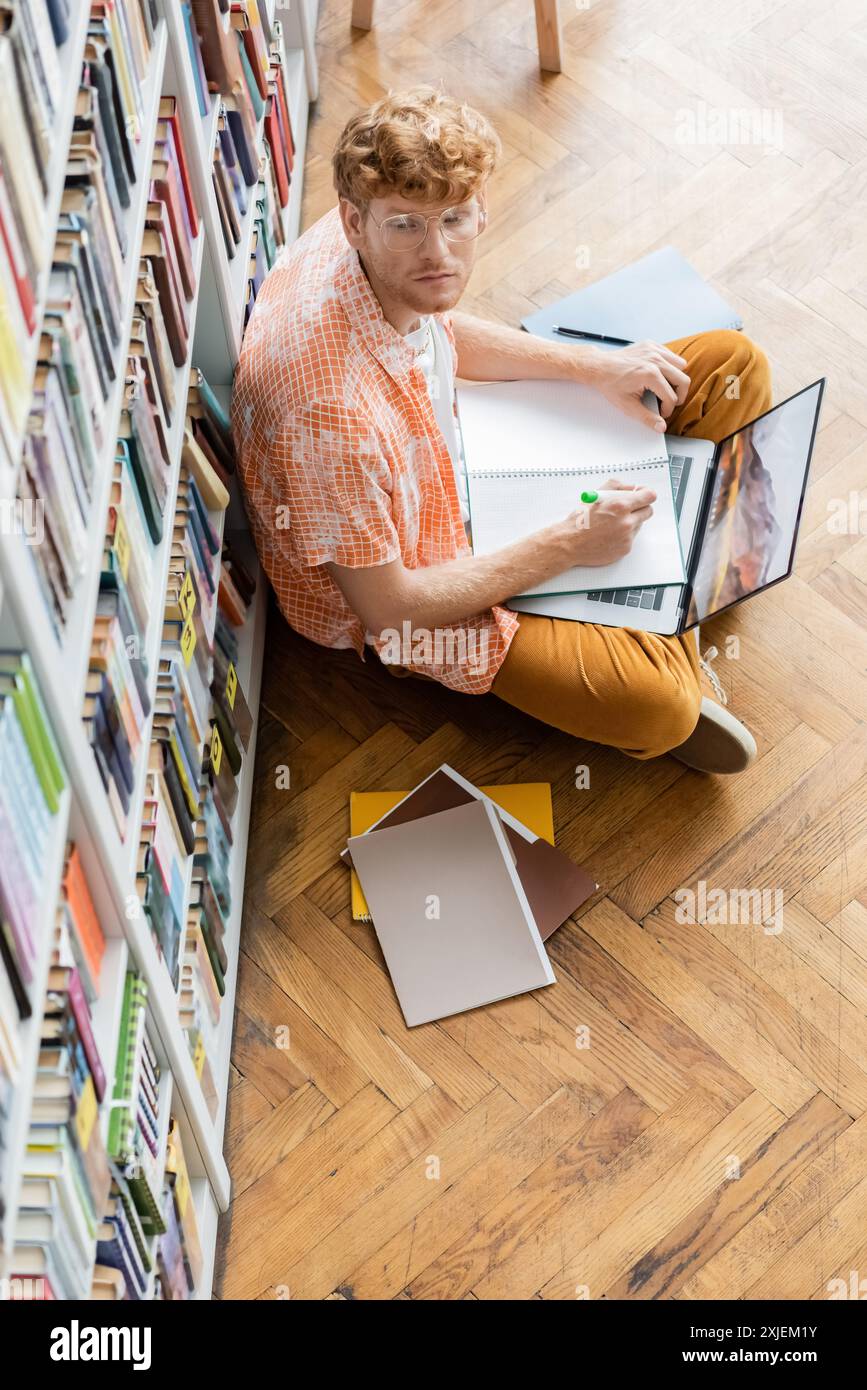 A young man seated before a library bookshelf Stock Photo - Alamy