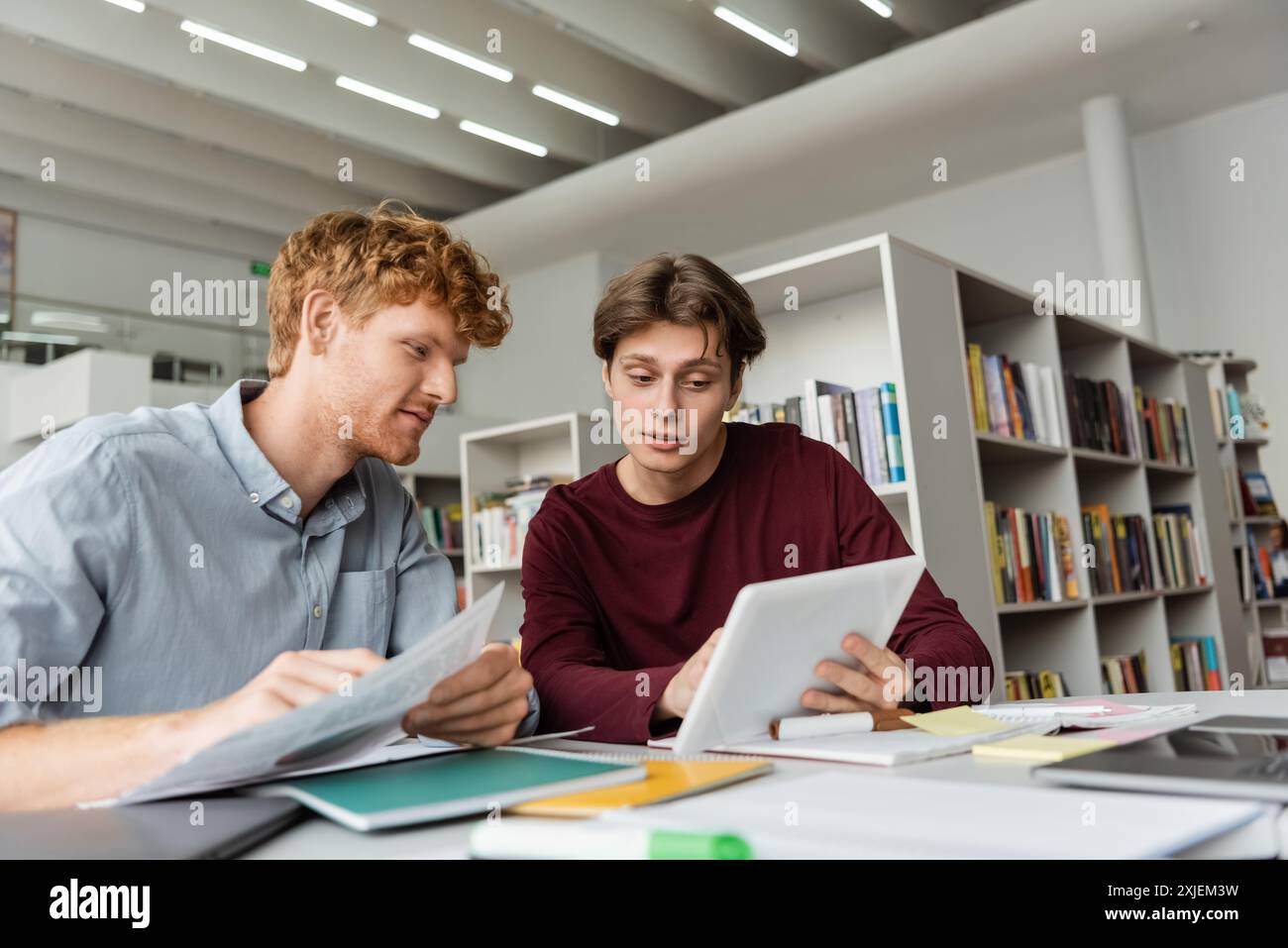 Two young men engage in studying together using a tablet Stock Photo ...