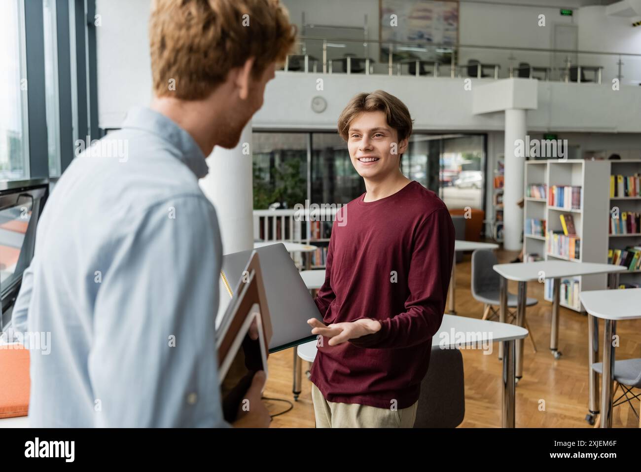 Two young men engaged in intense conversation amid rows of books in a ...