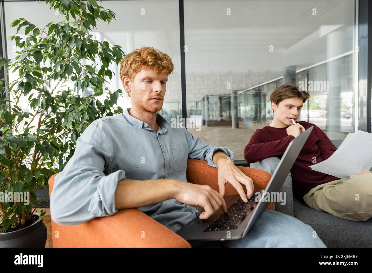 Two male students immersed in study while relaxing on a cozy couch ...