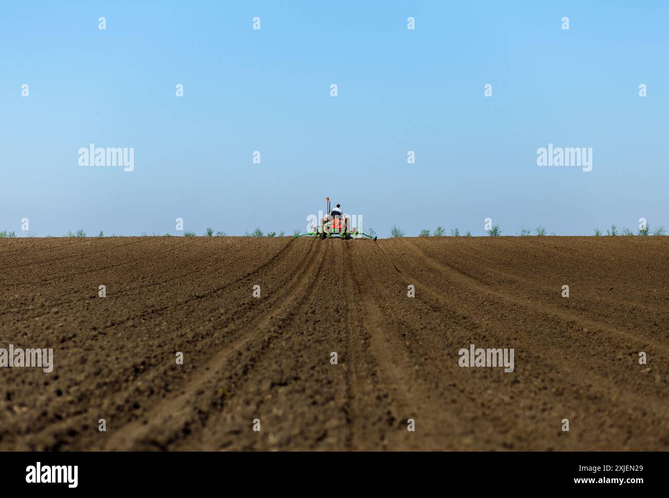 Farmer in old fashioned tractor sowing in field Stock Photo - Alamy