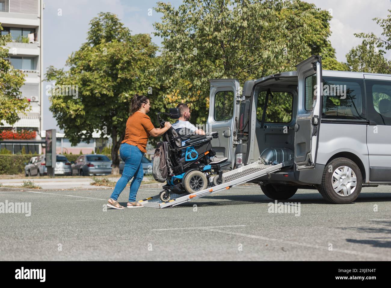 Female assistant transferring a man with disability into the vehicle by ...