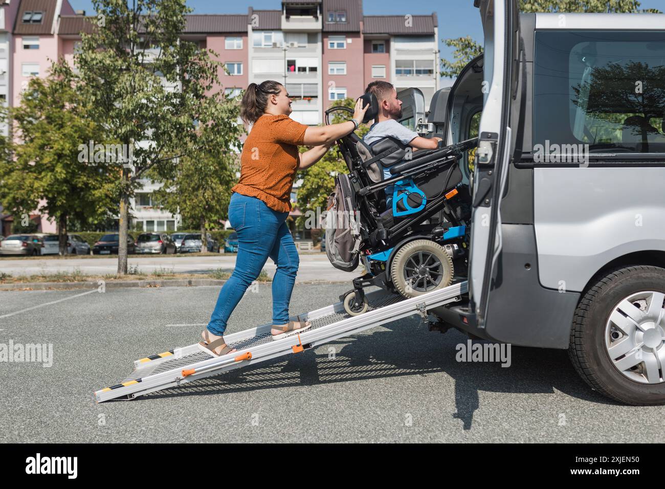 Female assistant helping a man with disability to enter an accessible ...