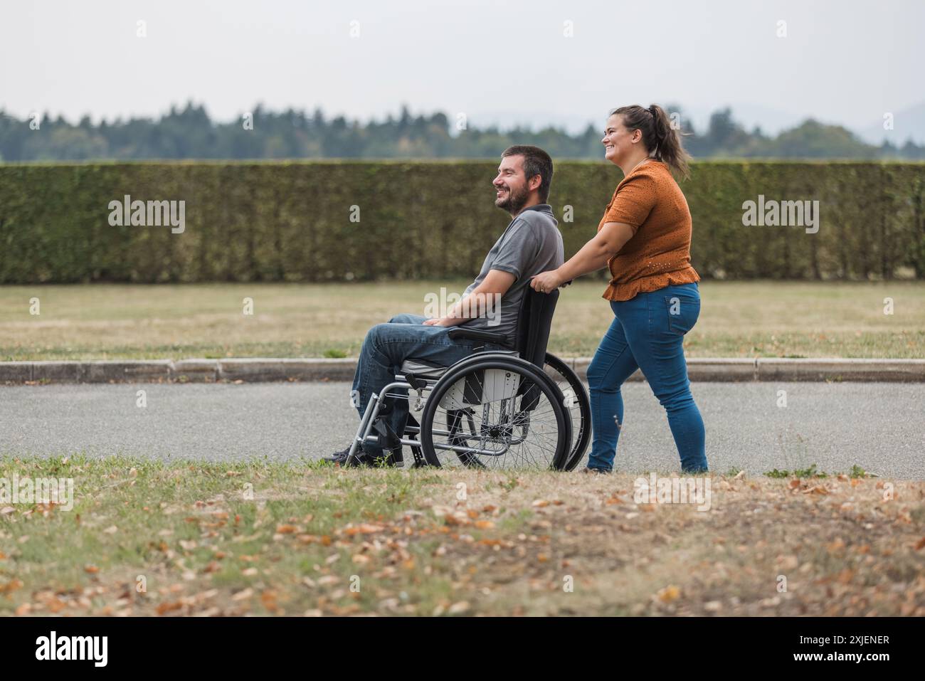 Personal assistant helping a man with disability to push a wheelchair ...