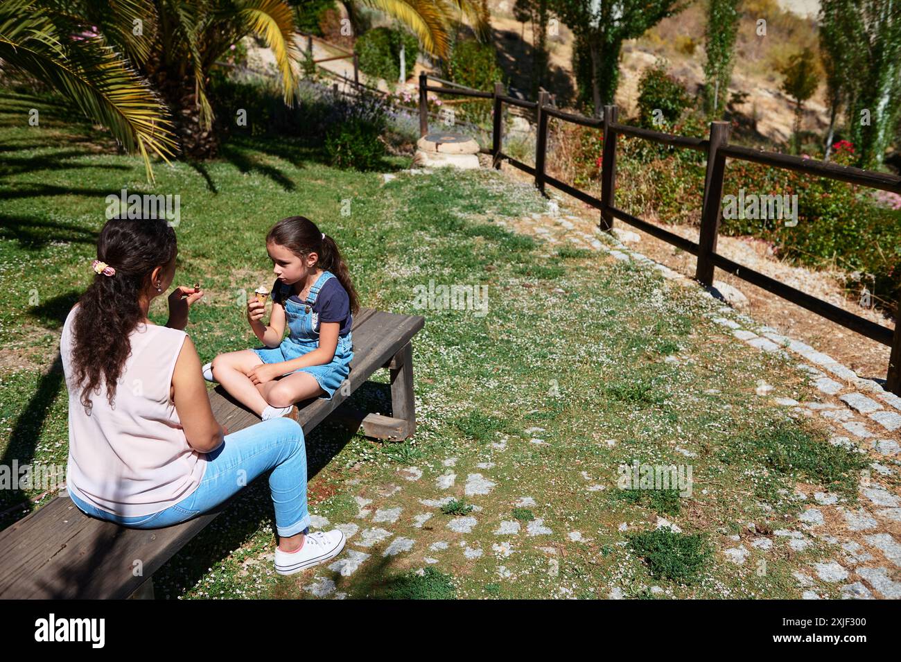 Mother and daughter share a moment of joy eating ice cream on a sunny ...