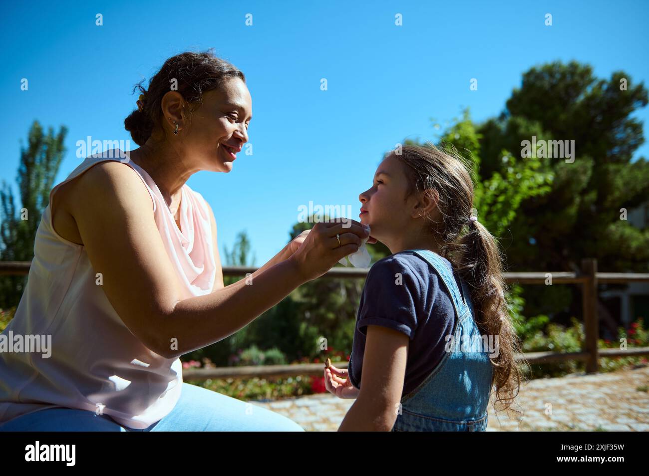 Mother applying sunscreen to her daughter on a bright sunny day ...