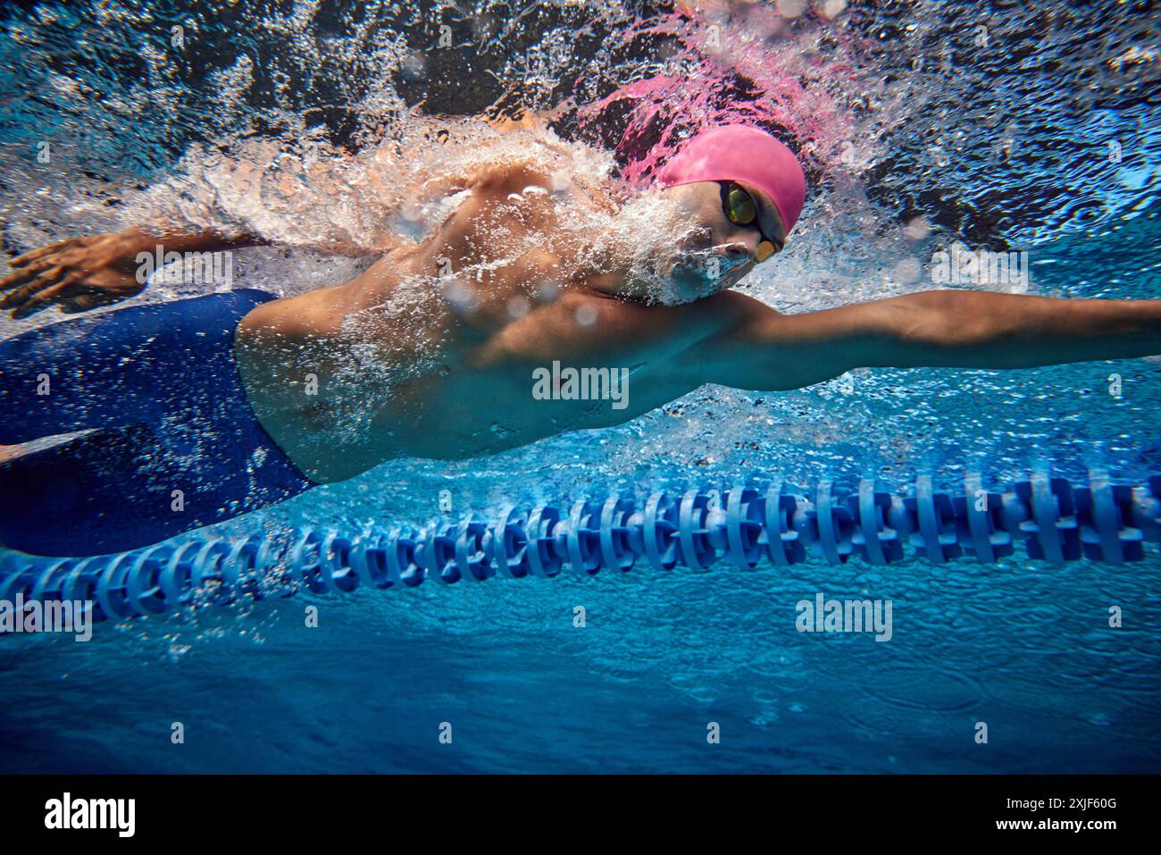 Focused swimmer, seen from below, cutting through water with strong ...