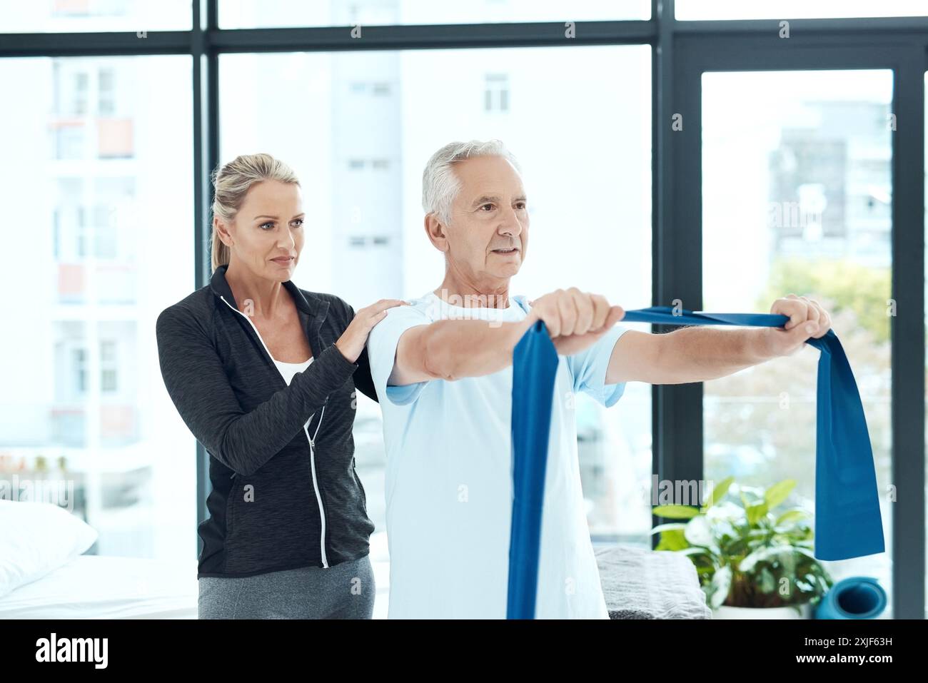 Mature, woman and resistance band with physiotherapist for physical ...