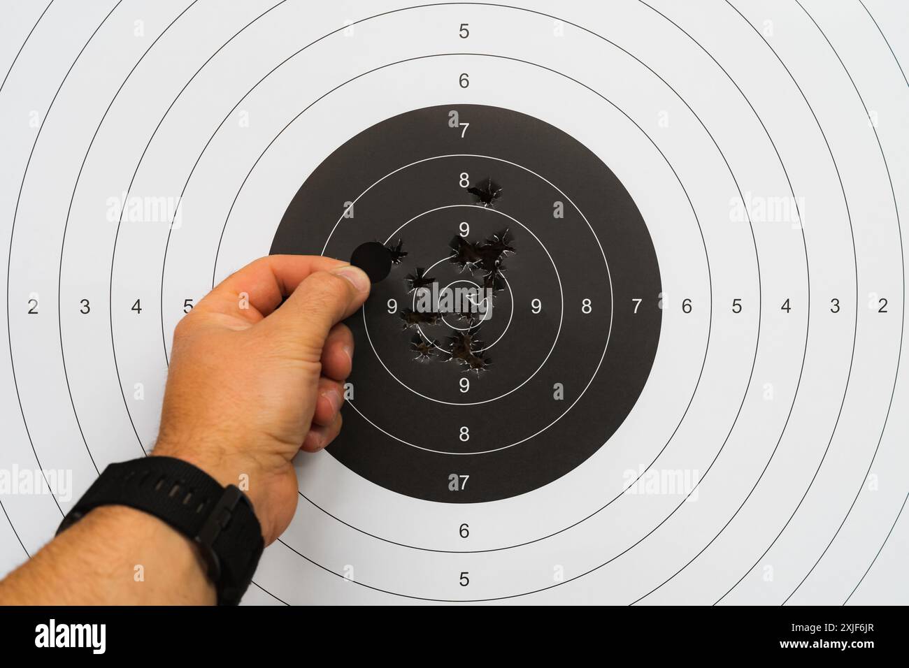 Accurate shooting at a shooting range, a man's hand seals bullet holes ...