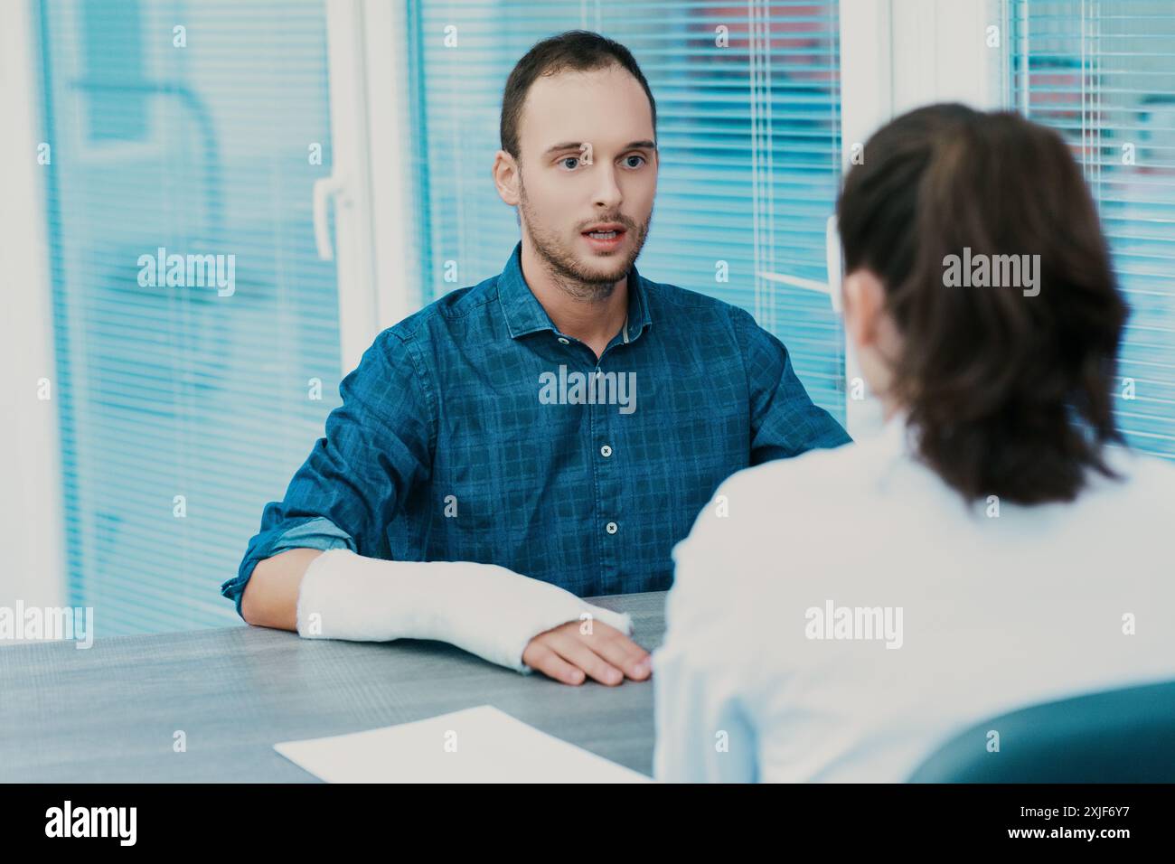 Young man with his arm in a cast is sitting in the doctor's office ...
