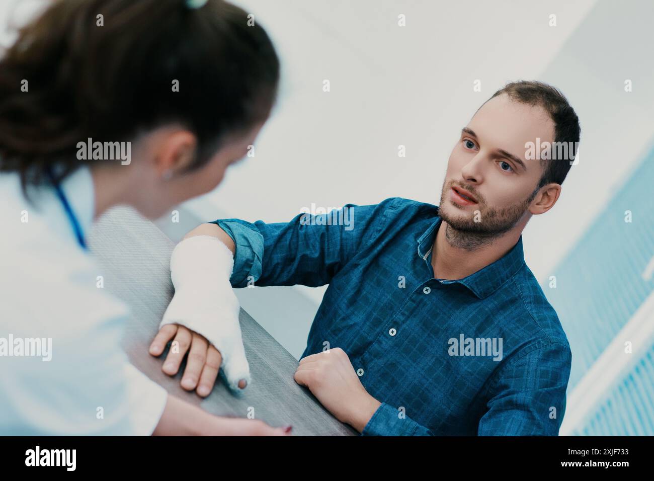 Doctor explains a broken arm to a patient in a hospital. Both listen ...
