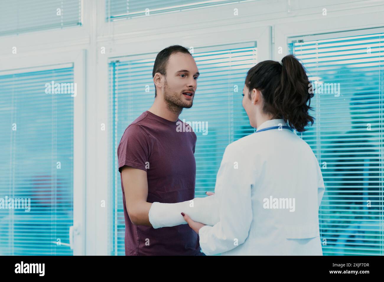 Doctor is holding the arm of her patient who is describing how he got ...