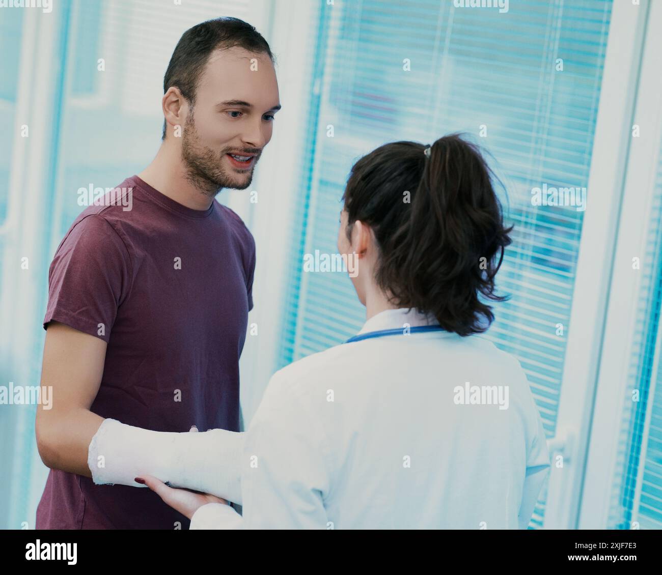 Smiling patient in a hospital room talks to a female doctor examining ...