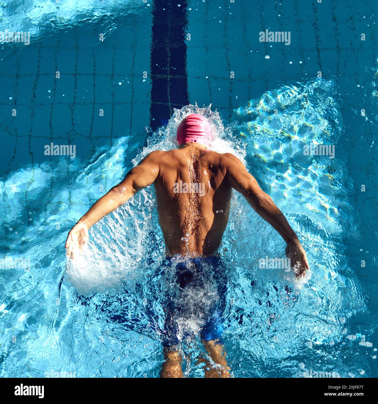 Overhead view swimmer in pink cap performs powerful butterfly stroke ...