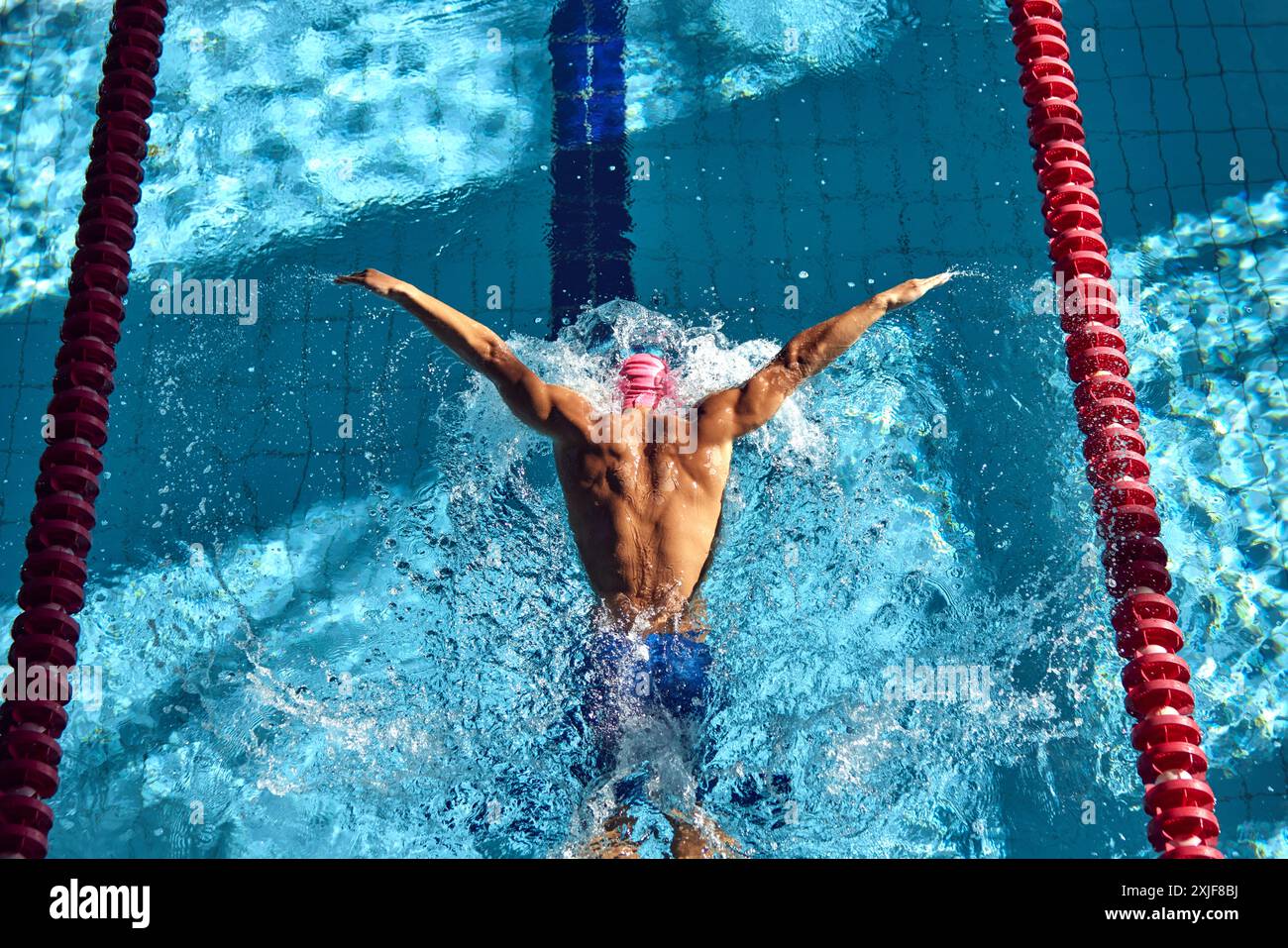 Swimmer, seen from above, powers through water with butterfly stroke ...