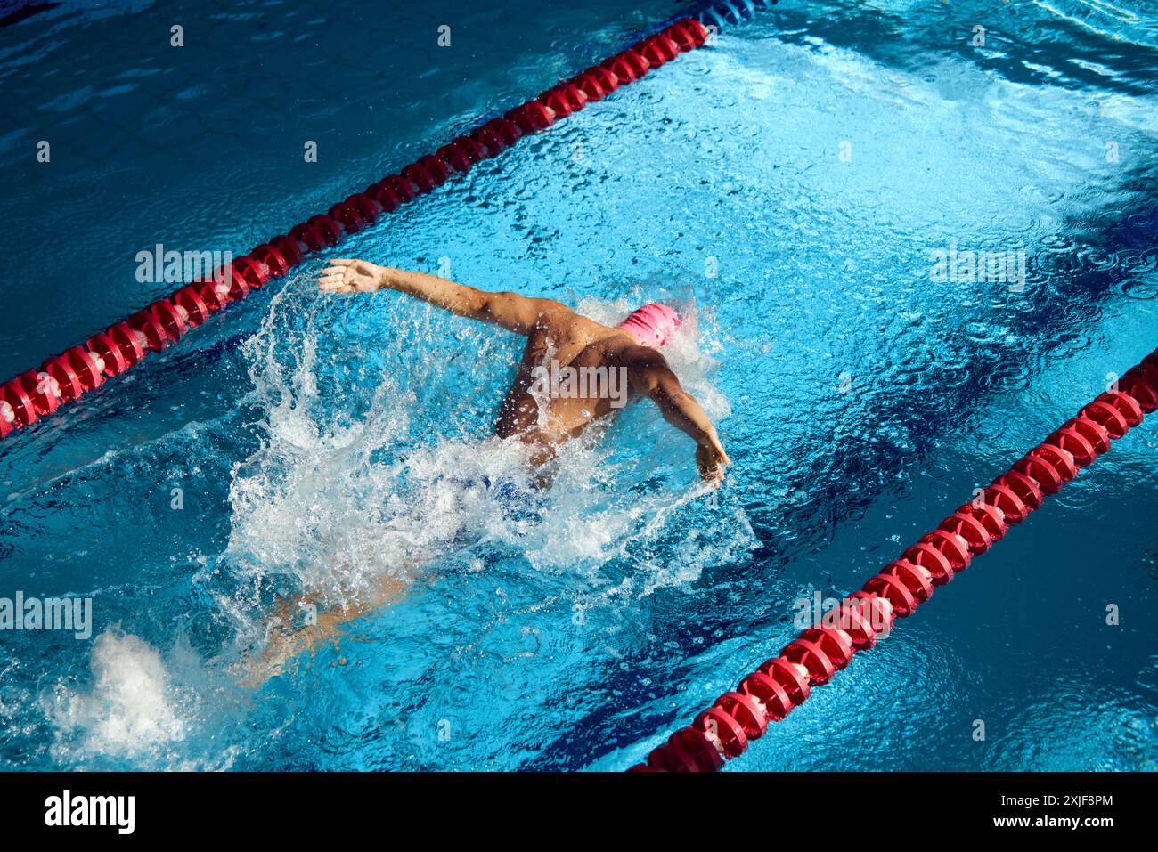 Swimmer in pink cap executes powerful butterfly stroke, his muscular ...
