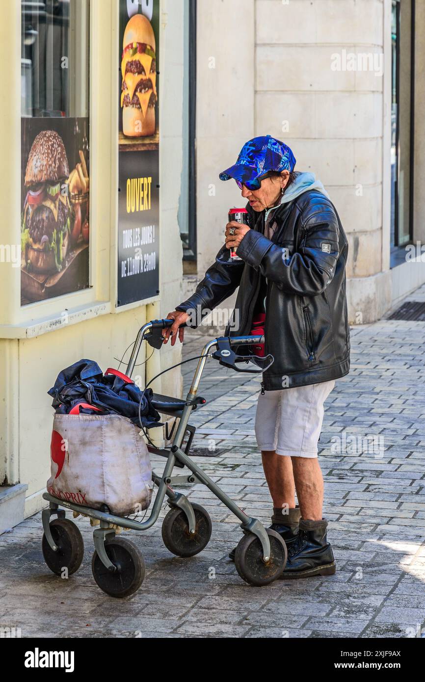 'Down and out' vagrant woman pushing trolley and drinking soda from can ...