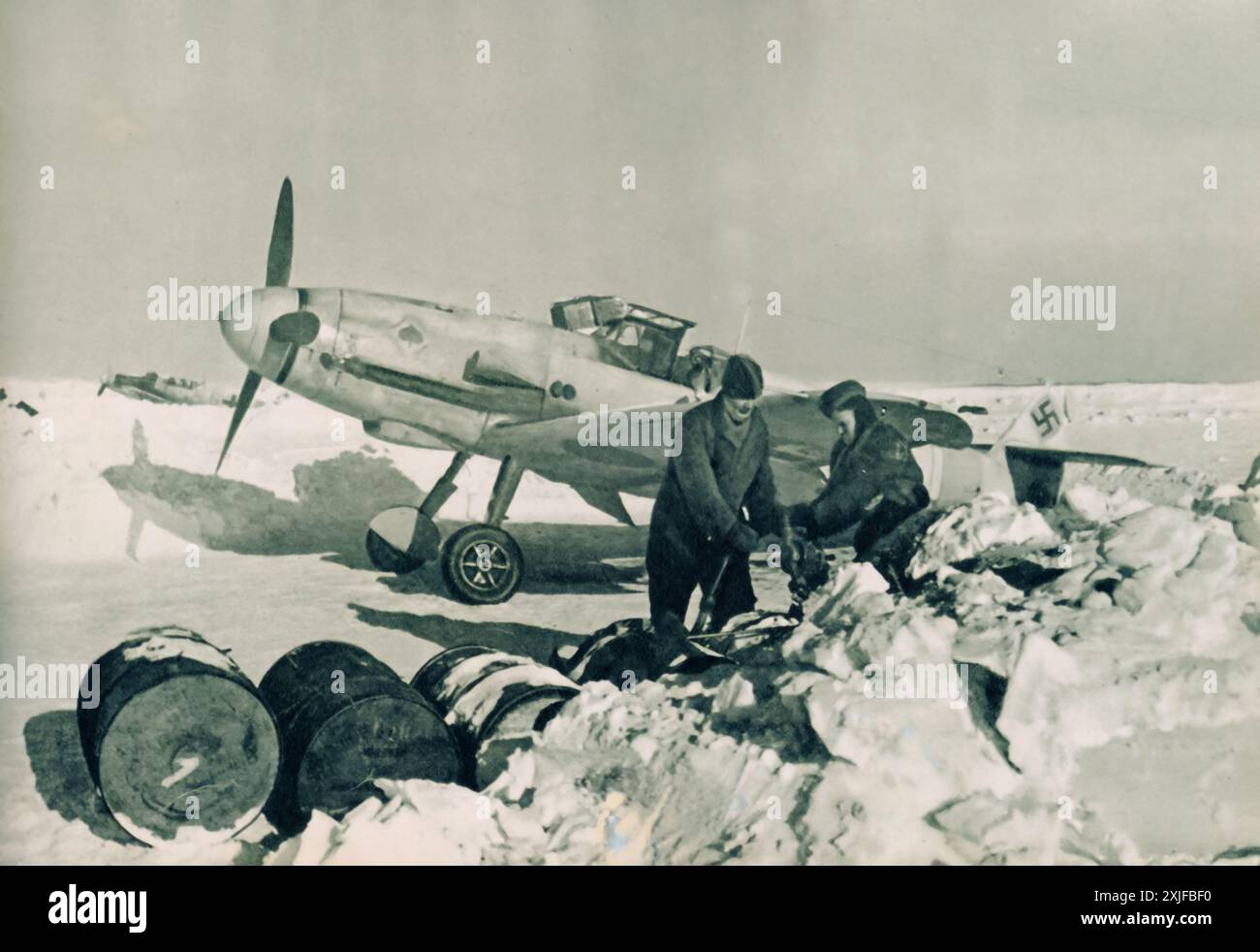 A photograph shows soldiers handling fuel barrels to refuel a ...