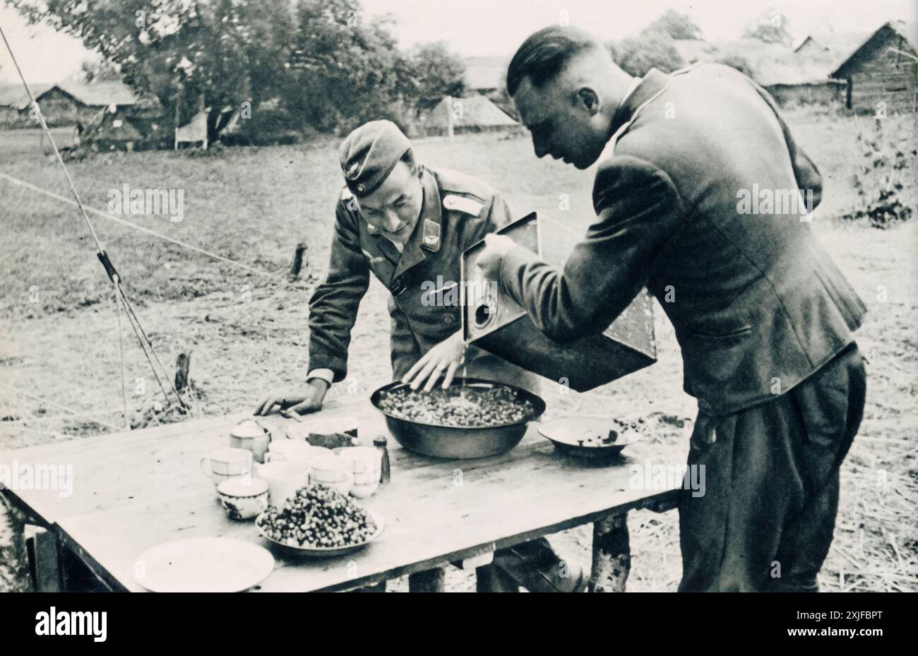 A photograph shows German soldiers at a temporary camp, preparing their ...