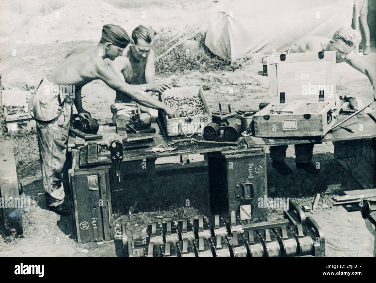 A photograph shows two German soldiers organizing ammunition boxes ...