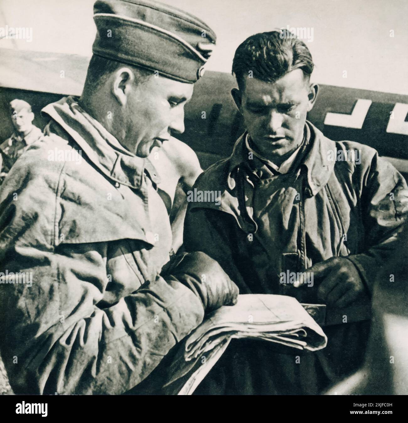 A photograph shows a pilot and an observer discussing their mission and ...