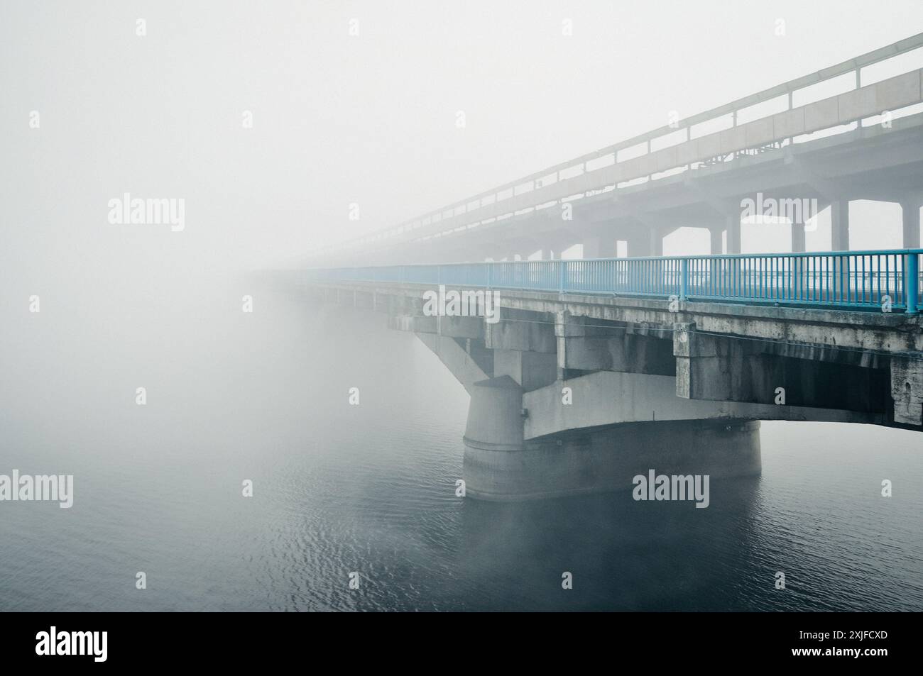Bridge to nowhere. Concrete bridge over a river covered in thick fog ...