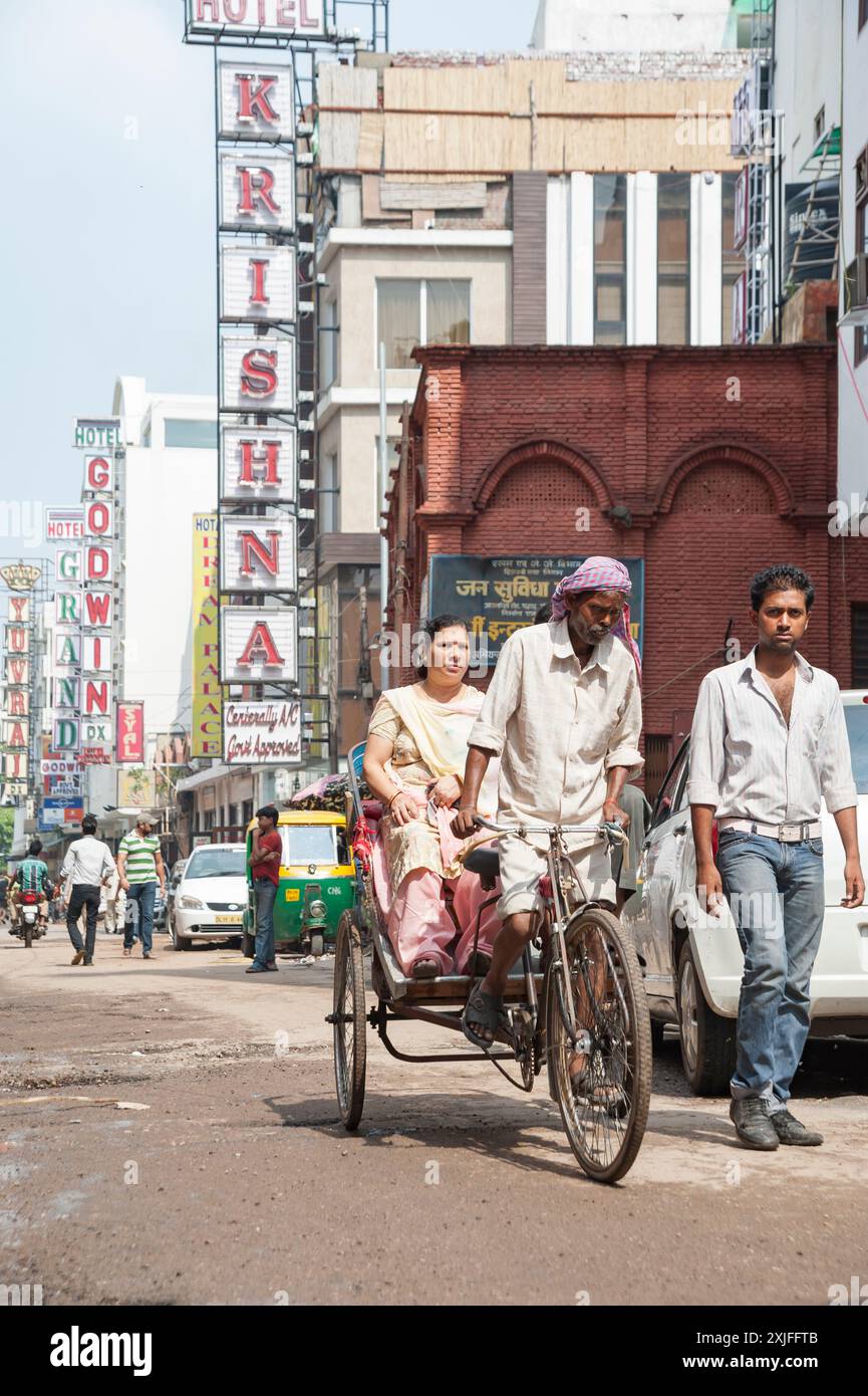 Street scene in New Delhi with men walking and a woman driving by in a ...