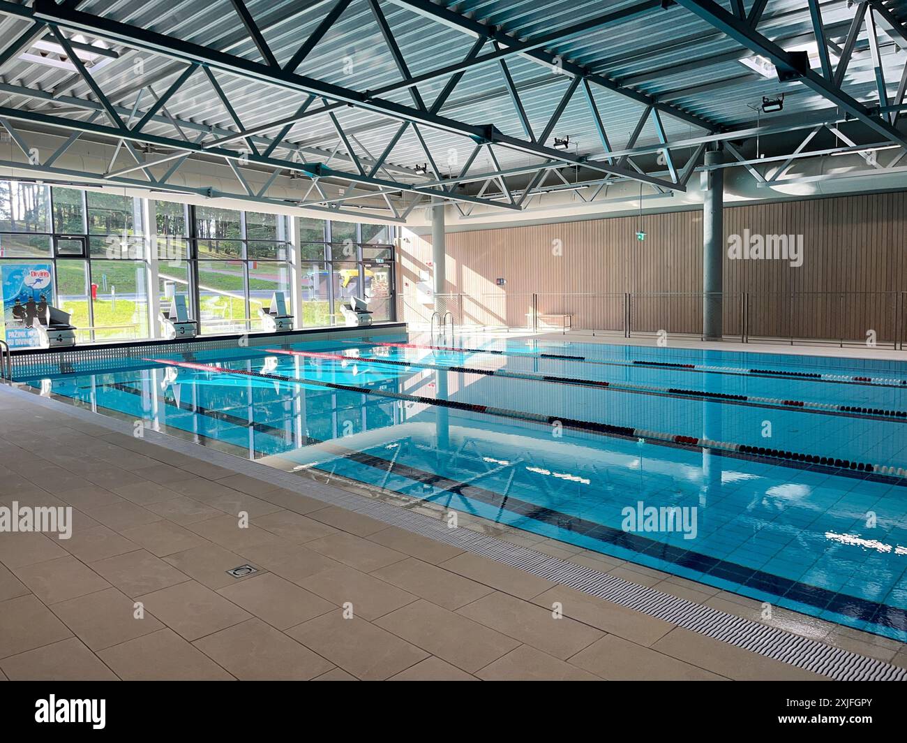 An indoor swimming pool with clear blue water and lane dividers under a ...