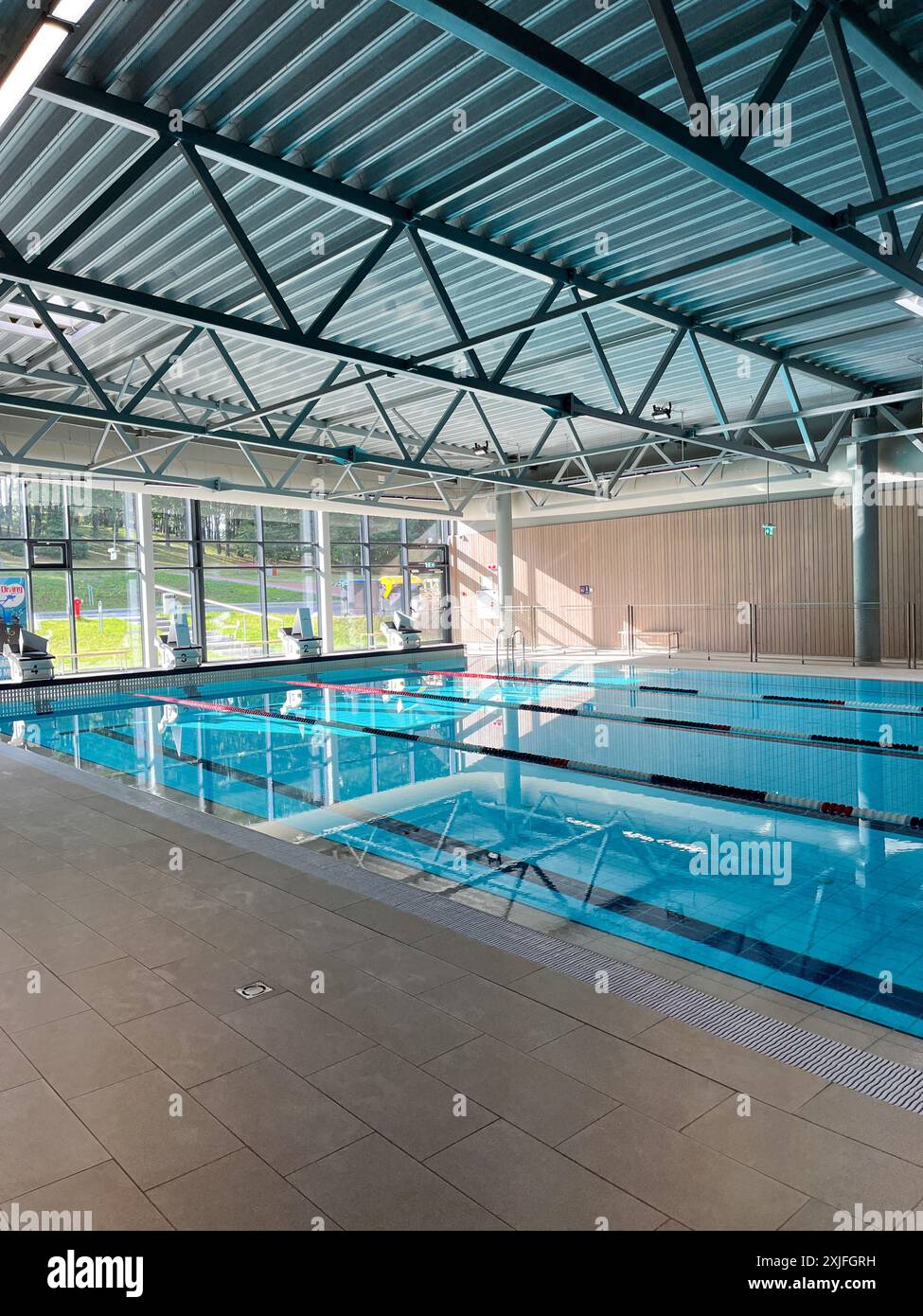 An indoor swimming pool with clear blue water and lane dividers under a ...