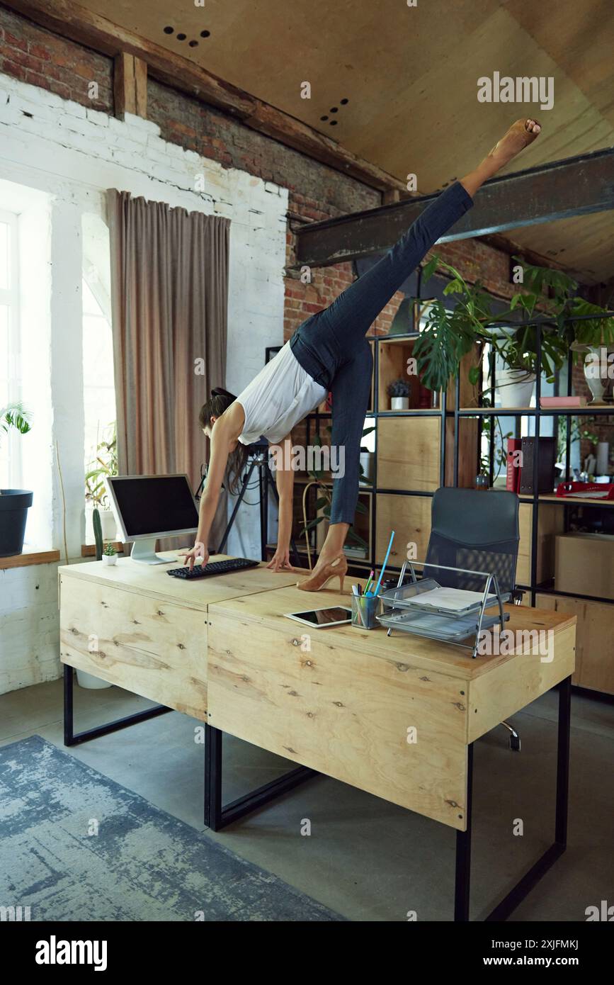 Combination of work and exercises. Woman standing on desk, working with ...