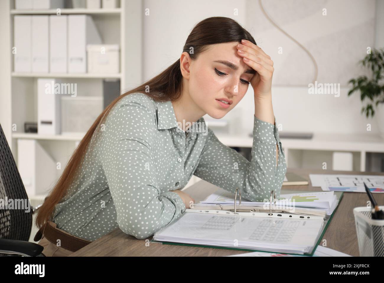 Embarrassed woman at wooden table with documents in office Stock Photo ...