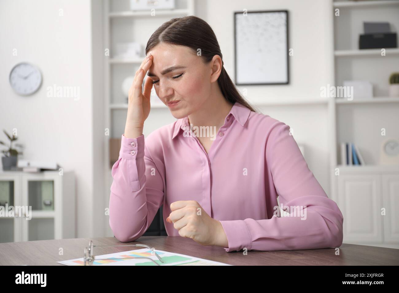 Embarrassed woman at wooden table in office Stock Photo - Alamy