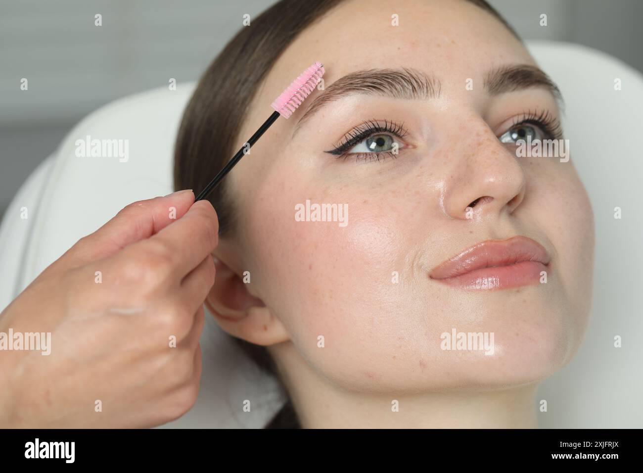 Beautician brushing young woman's eyebrow in beauty salon, closeup ...