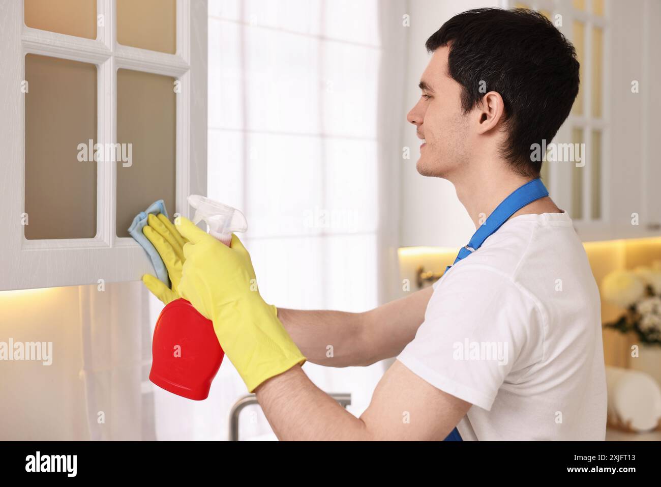 Professional janitor wearing uniform cleaning cabinet in kitchen Stock ...