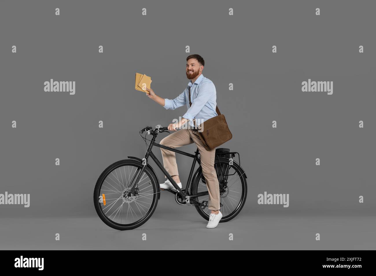 Postman on bicycle delivering letters against grey background Stock ...