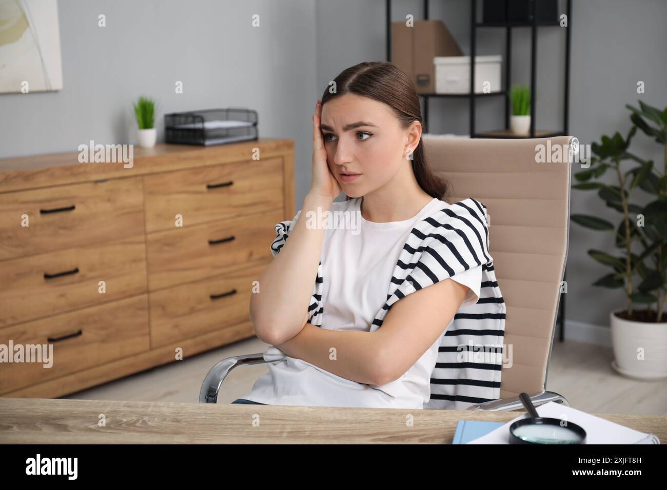 Embarrassed woman at wooden table in office Stock Photo - Alamy