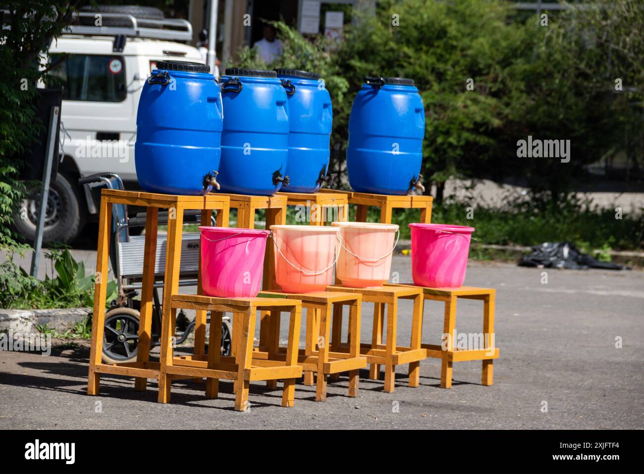 Plastic barrels with 0.5% chlorine solution on metallic stands serve as ...