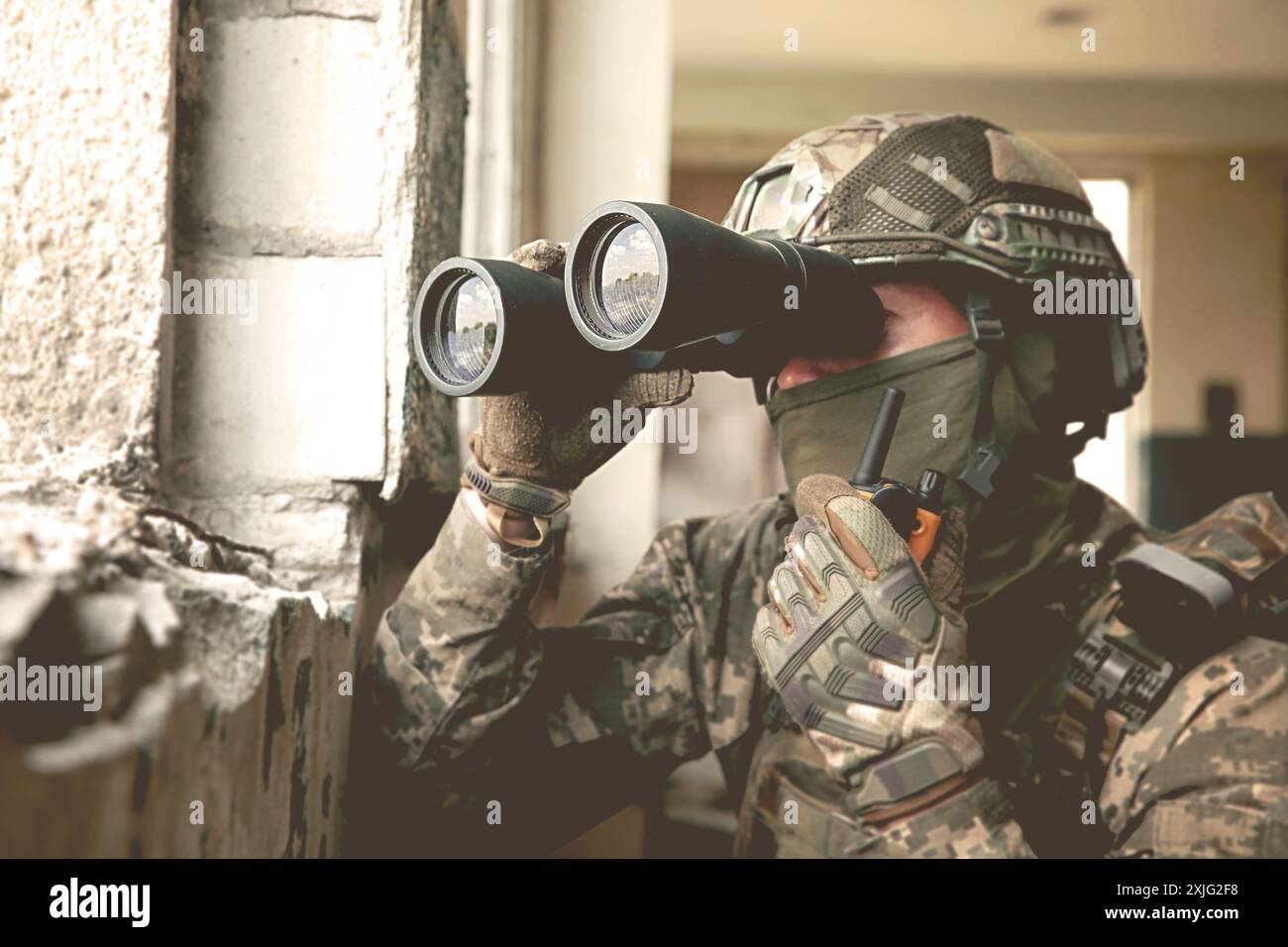 Soldier using radio and binoculars in building during military ...