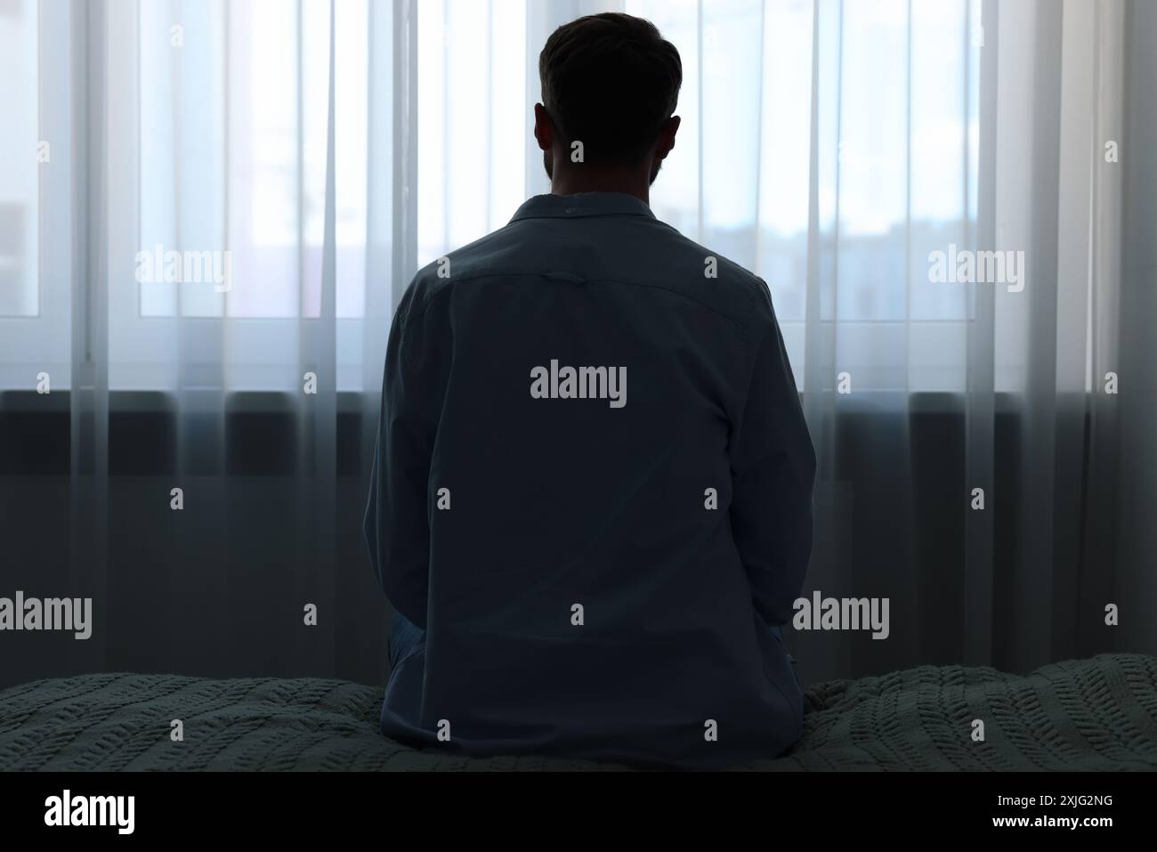 Loneliness concept. Sad man sitting on bed at home, back view Stock ...