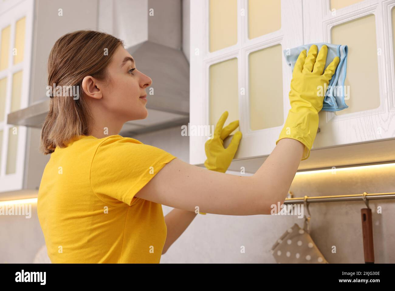Professional janitor wearing uniform cleaning cabinet in kitchen Stock ...