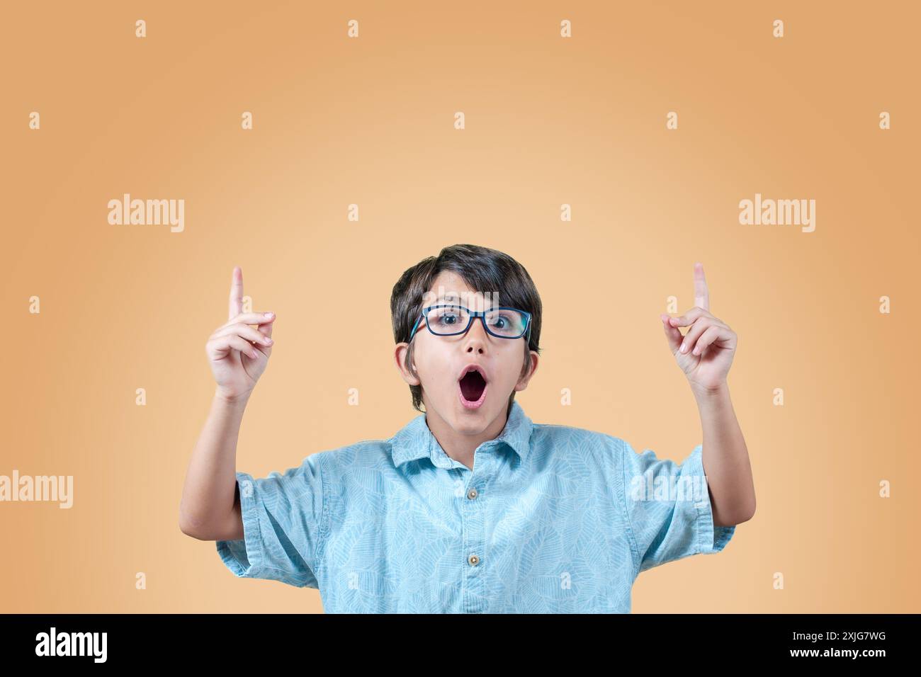 Surprised kid pointing up isolated on orange background Stock Photo - Alamy