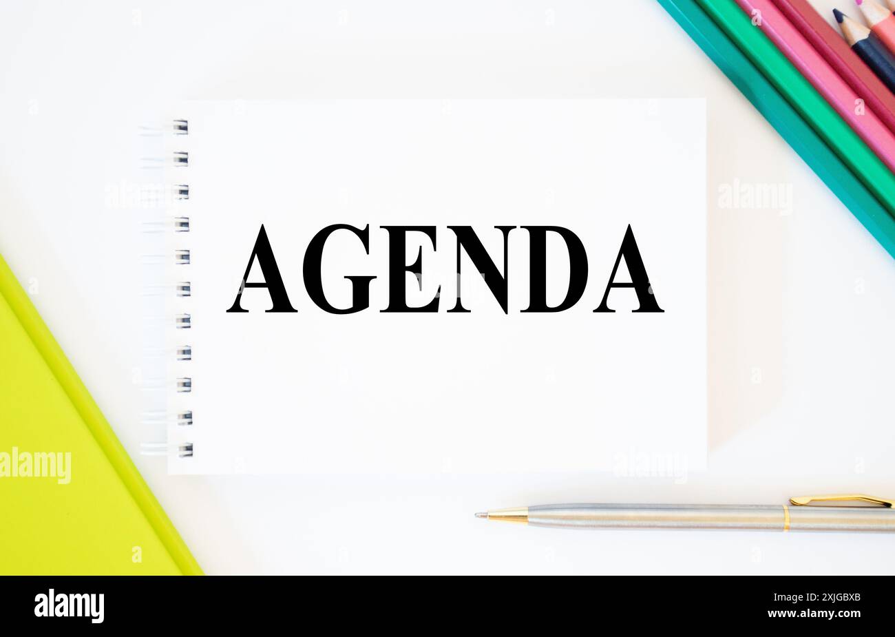 Top view of pen and notebook written with Agenda on white background ...