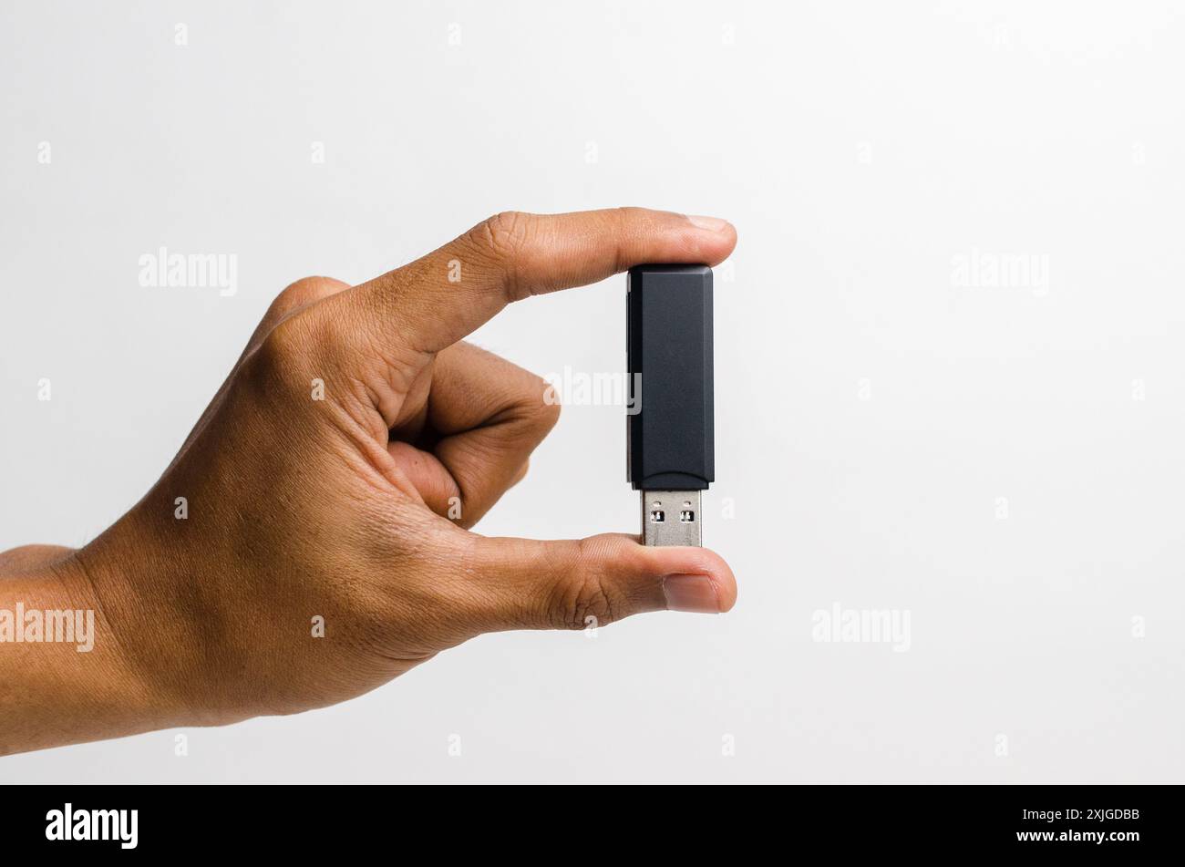 Man's hand holding a black USB flash drive in his hand with his ...